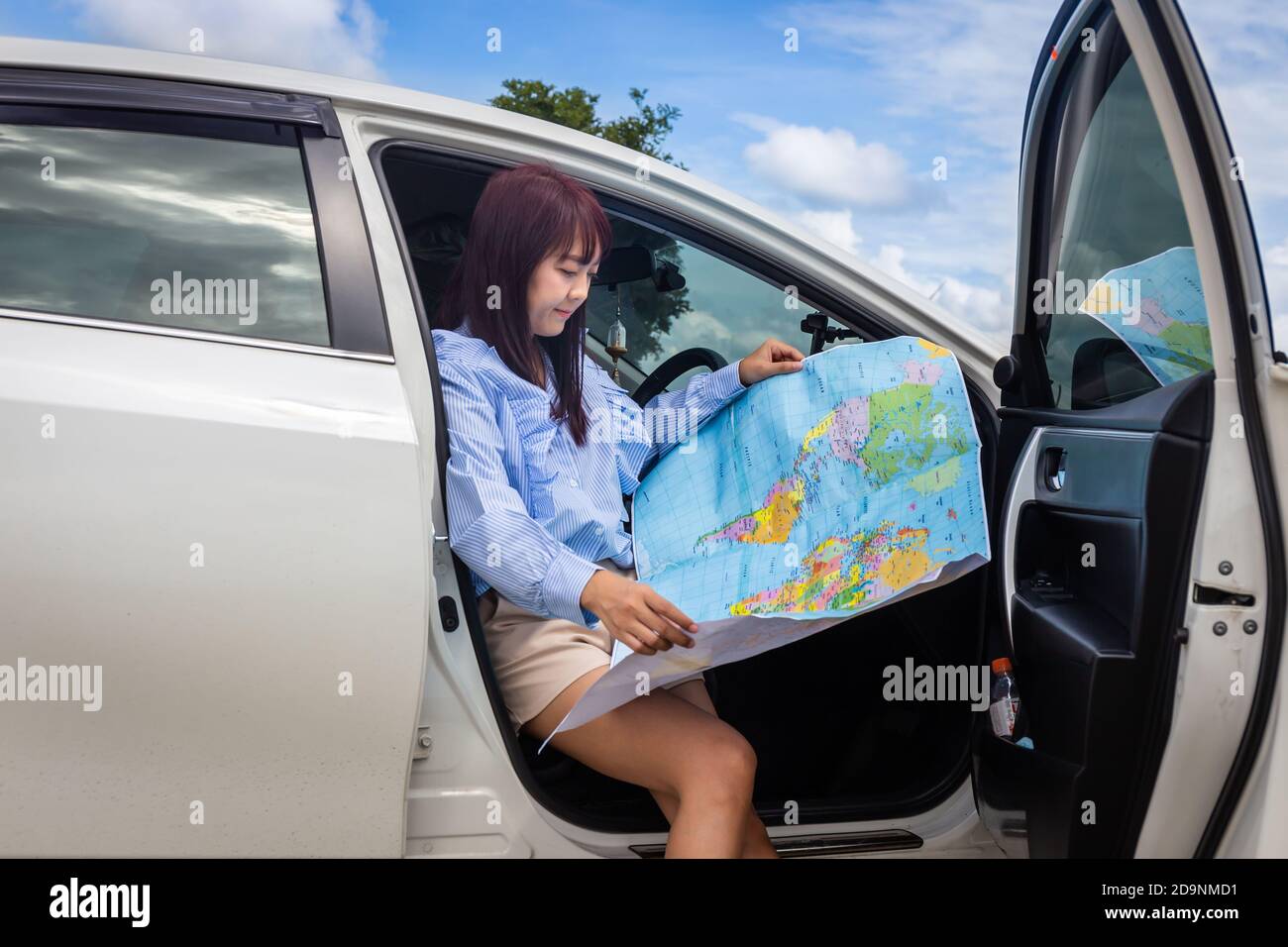 woman in a car looking at a map to reach the holiday destination with ...