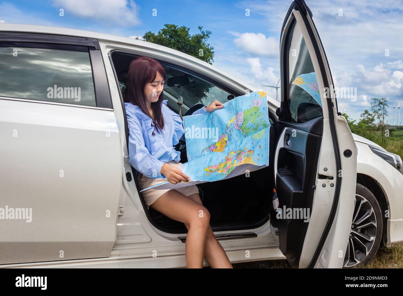 woman in a car looking at a map to reach the holiday destination with ...