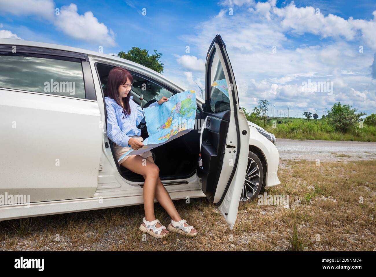 woman in a car looking at a map to reach the holiday destination with ...