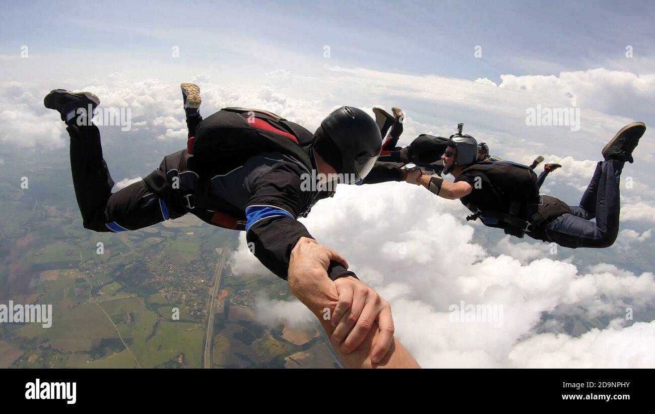 A group of friends holding hands teamwork in skydiving, soft focus on ...