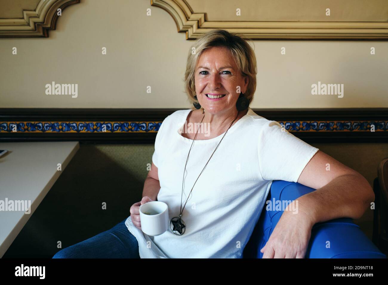 lady drinking coffee in cafeteria smiling and relaxed Stock Photo - Alamy