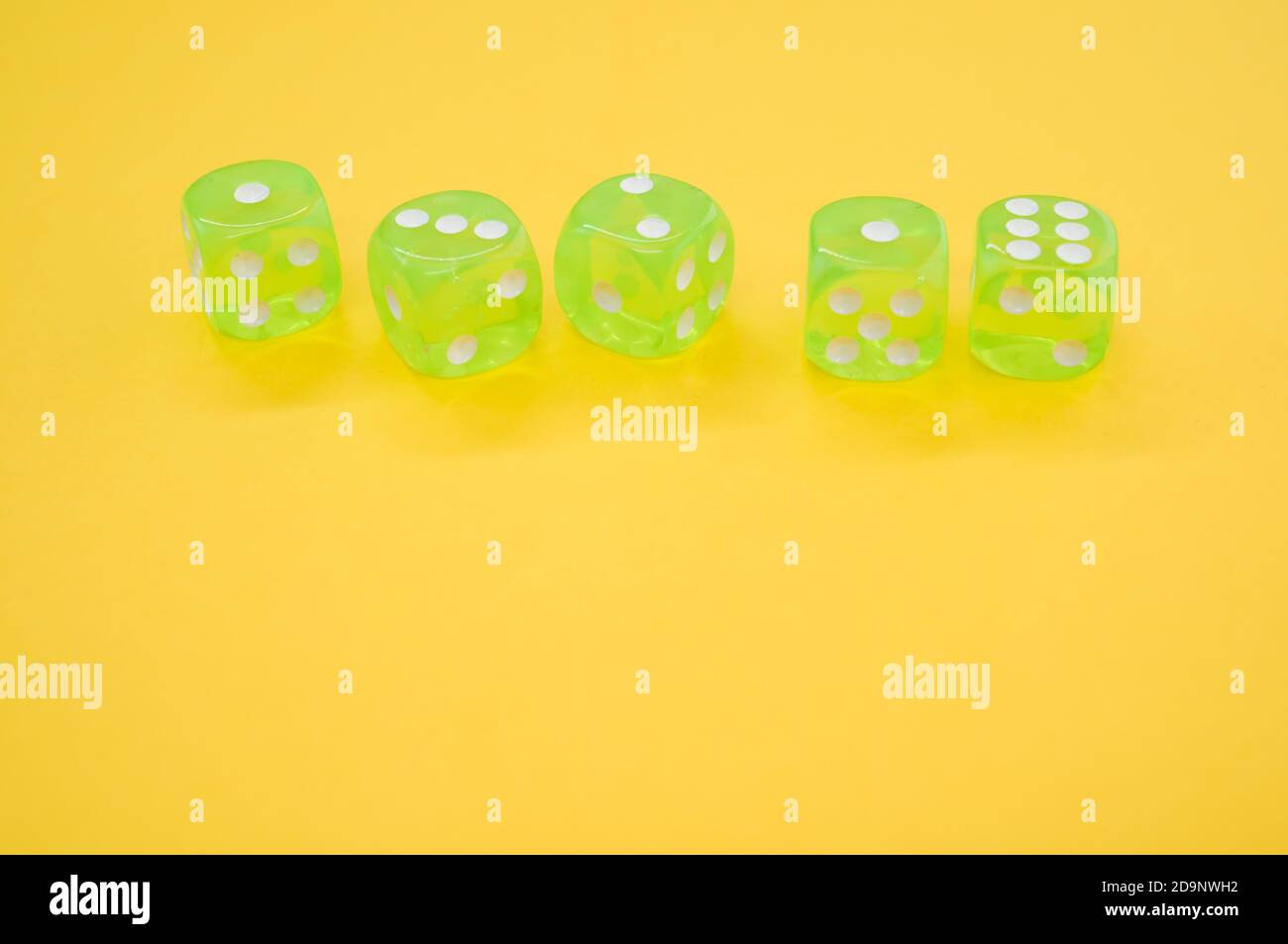 A top view closeup of five neon green dice isolated on a yellow ...