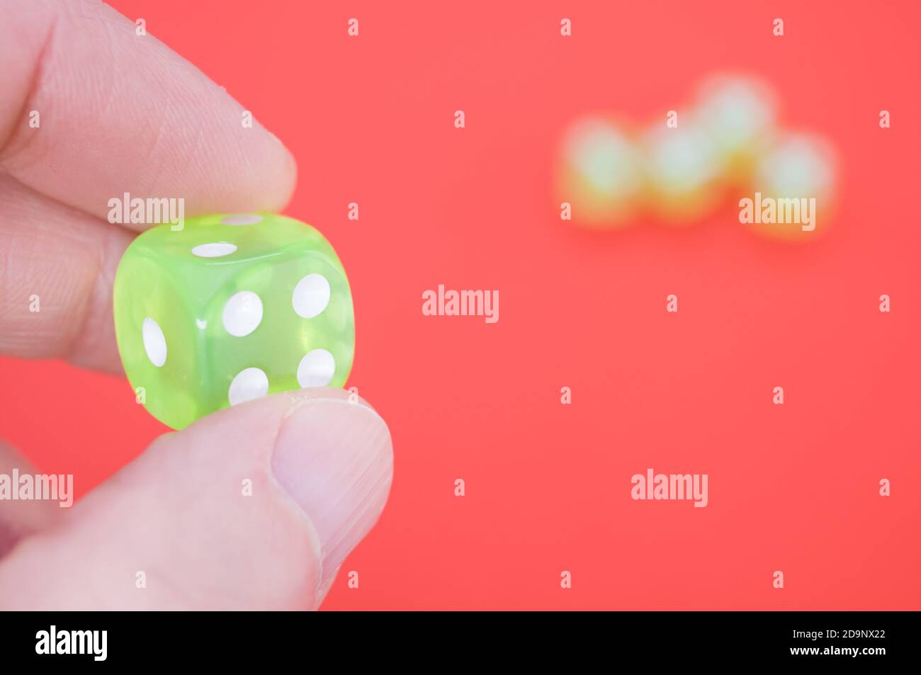 A closeup of a person's fingers holding a single neon green dice ...