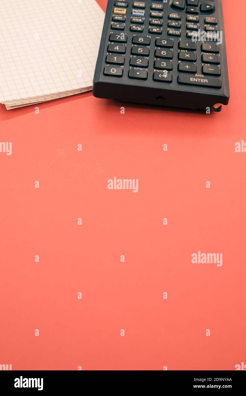 A top view closeup of a graphing calculator and a tiny notepad isolated ...