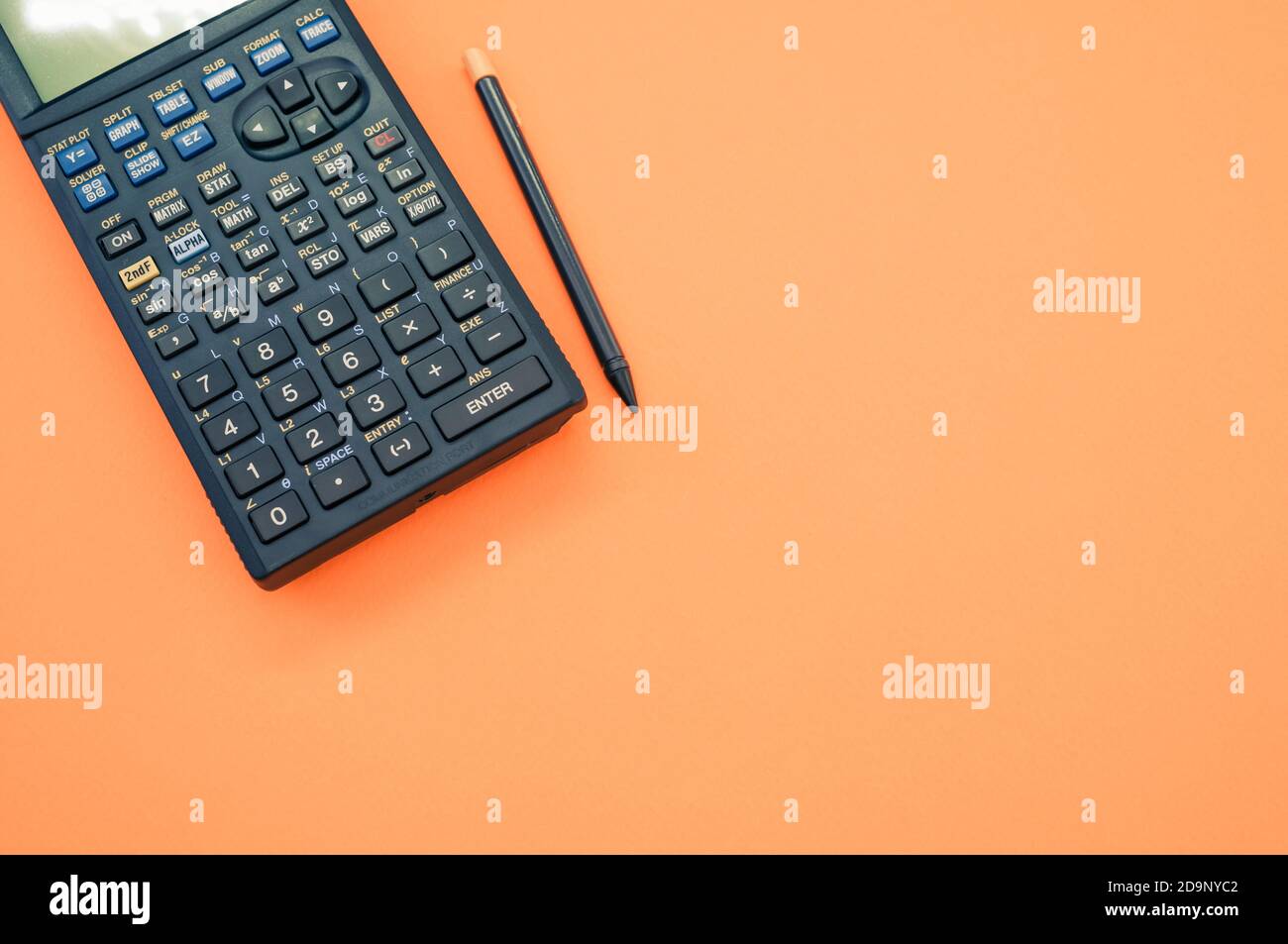 A top view closeup of a graphing calculator and a tiny pen isolated on ...