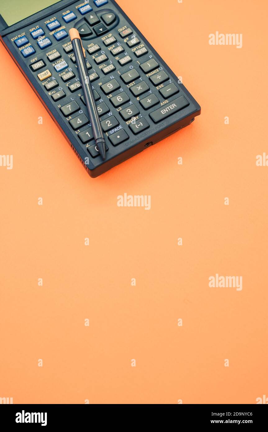 A top view closeup of a graphing calculator and a tiny pen isolated on ...