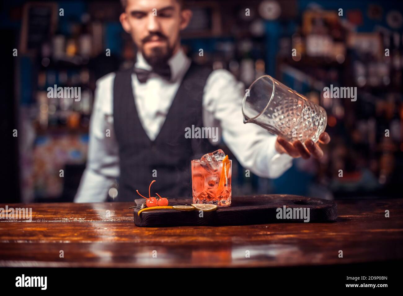 Focused bartender intensely finishes his creation while standing near ...