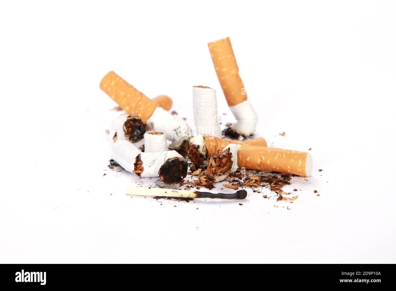 A pile of smoked old cigarettes and used matches isolated on a white ...