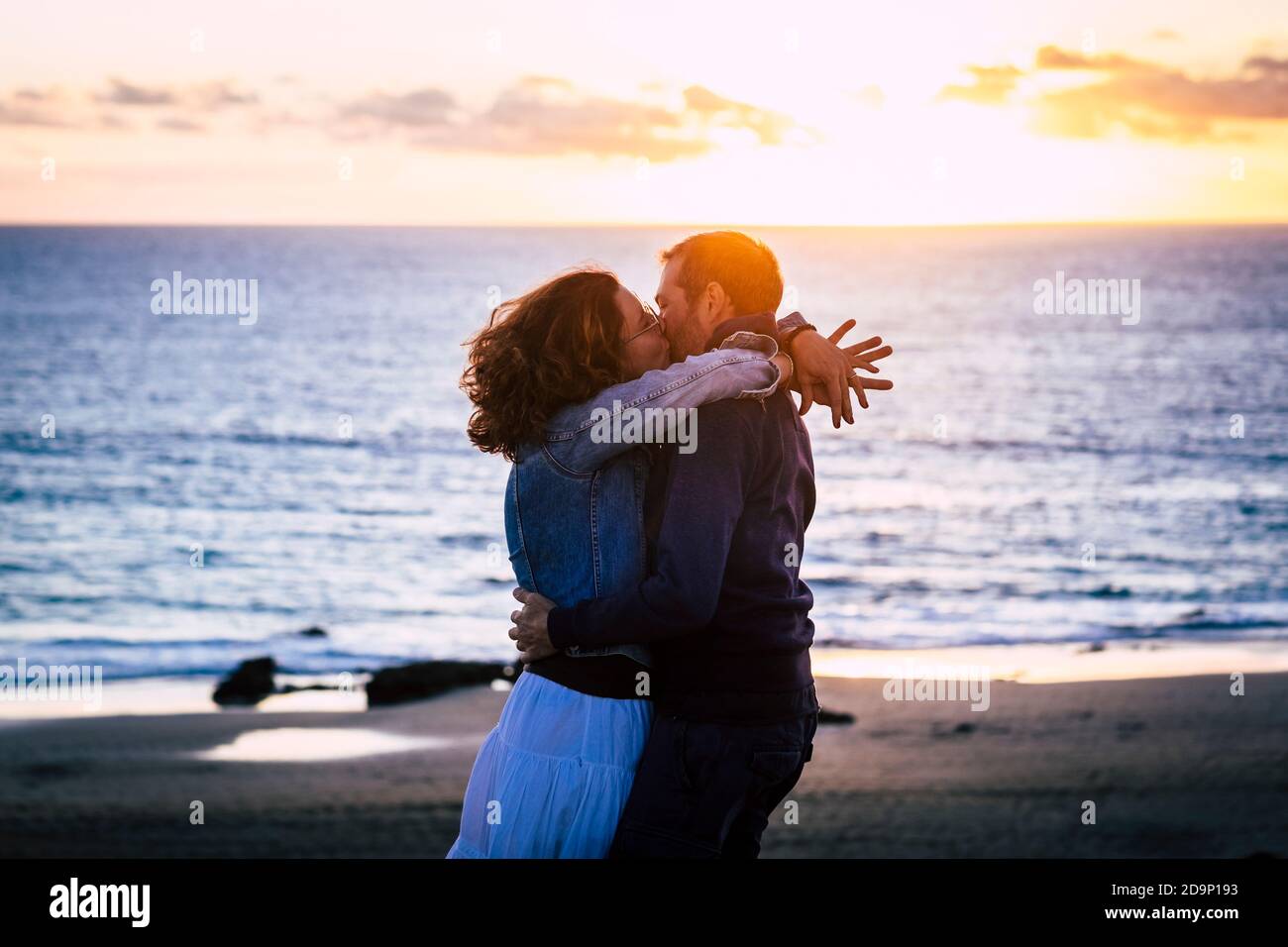 Romantic couple enjoying sunset at the beach kissing and loving each ...