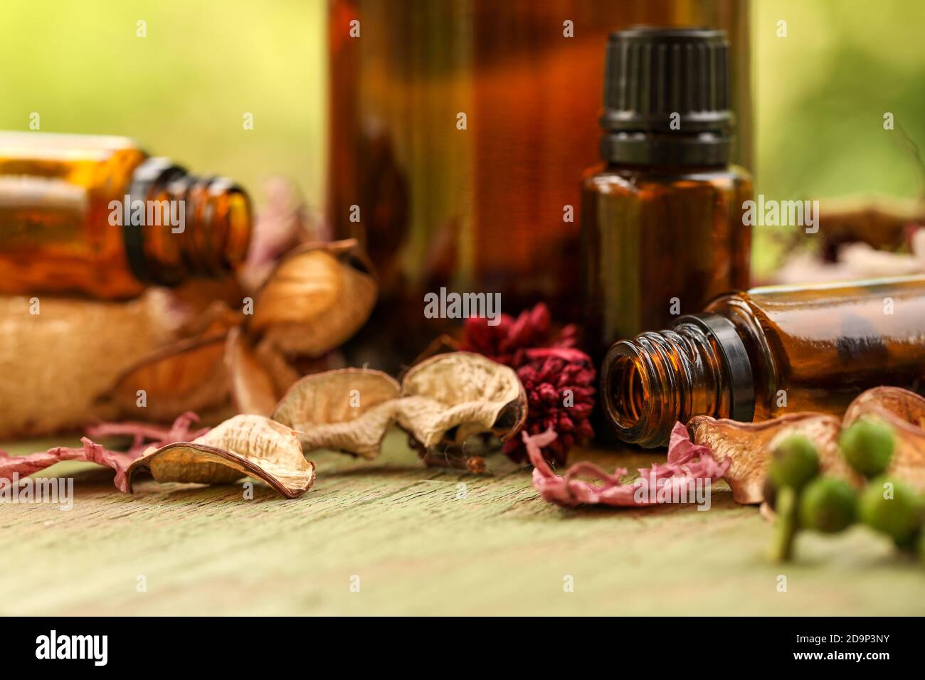 Closeup shot of amber essential oil bottles surrounded by dried flowers ...