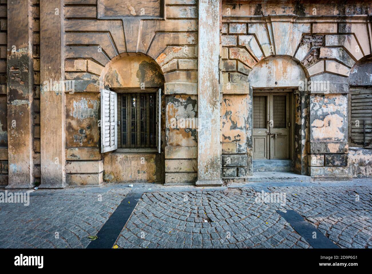 View of an old stone built wall and pavement on the street of Kolkata ...