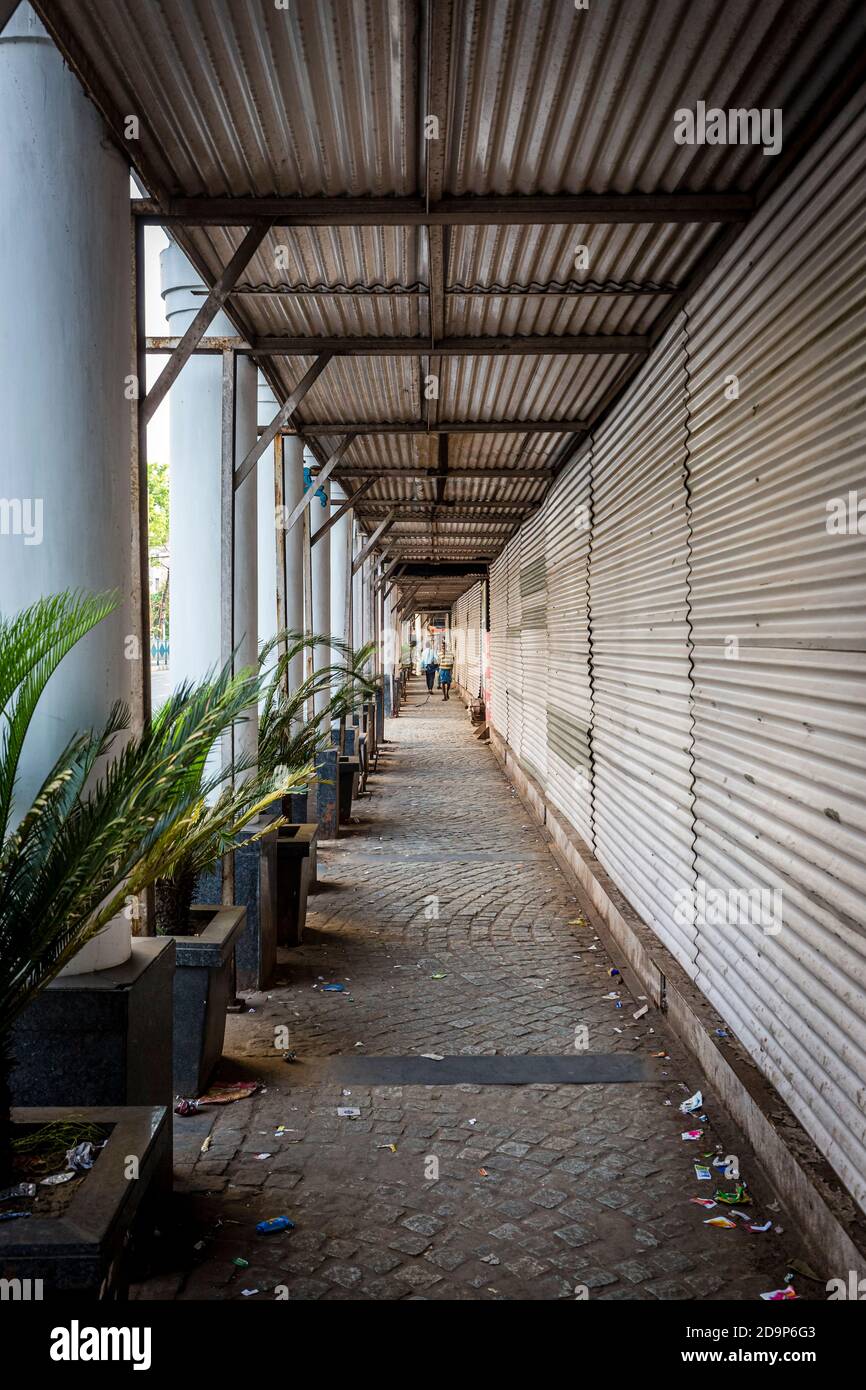 View of an empty and dirty corridor with closed shutters of shops in ...