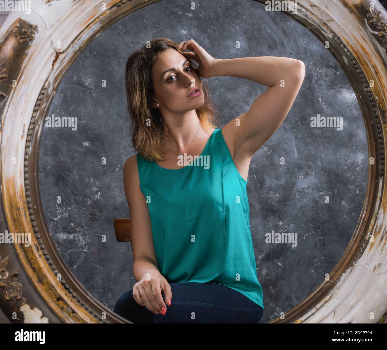 Beautiful young woman looking on her reflection at the mirror studio ...