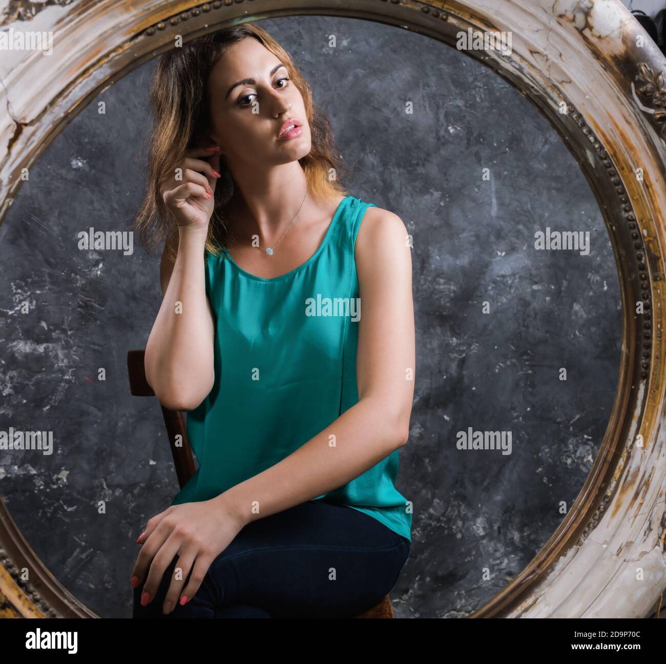 Beautiful young woman looking on her reflection at the mirror studio ...