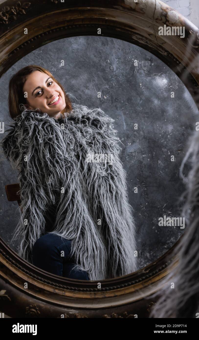 Beautiful young woman looking on her reflection at the mirror studio ...