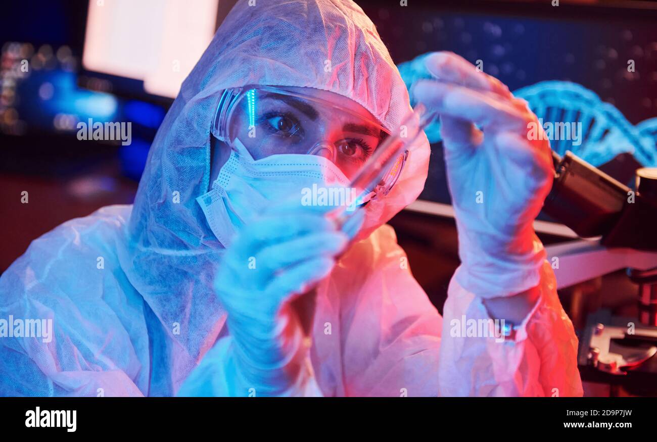Nurse in mask and white uniform, holding tube with liquid and sitting ...