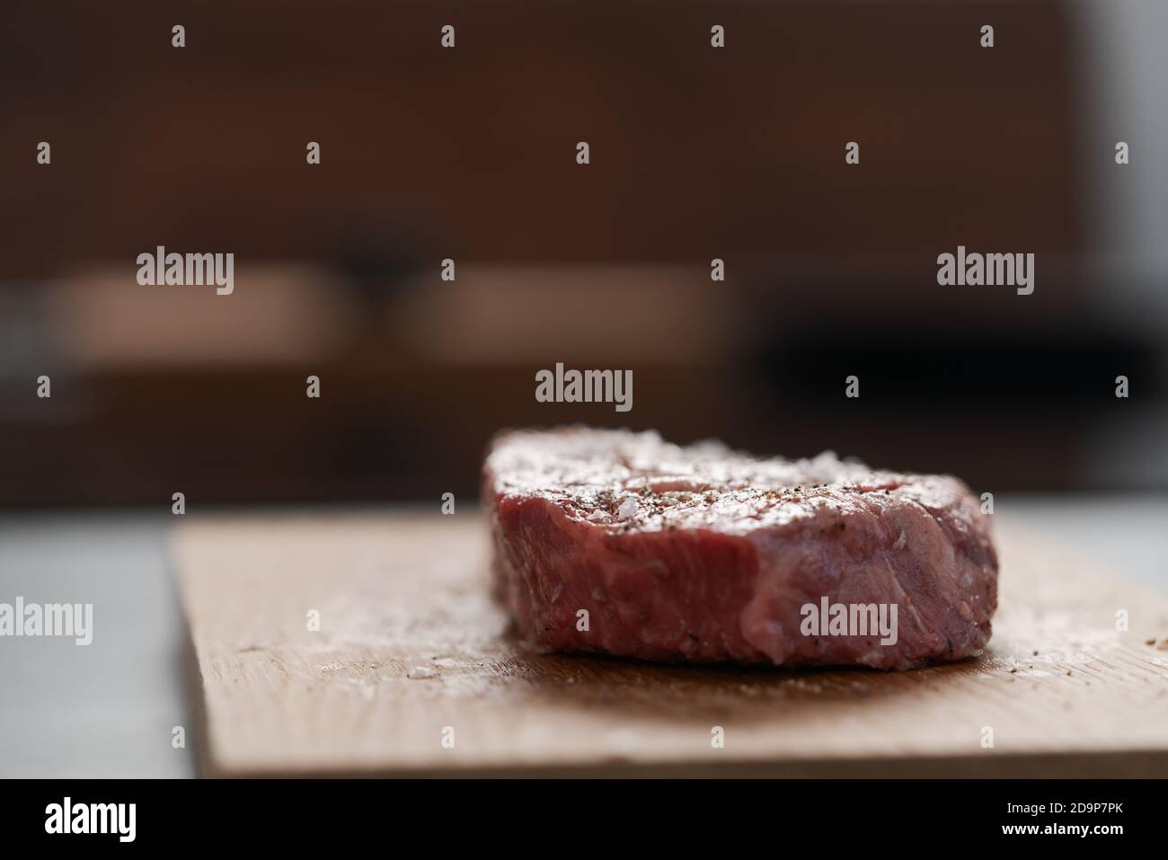 Raw ribeye steak spiced and ready to cook on oak board , shallow focus ...