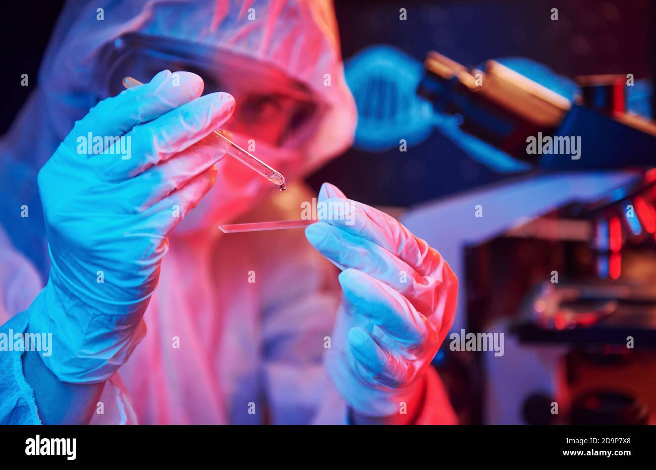 Nurse in mask and white uniform, holding tube with liquid and sitting ...