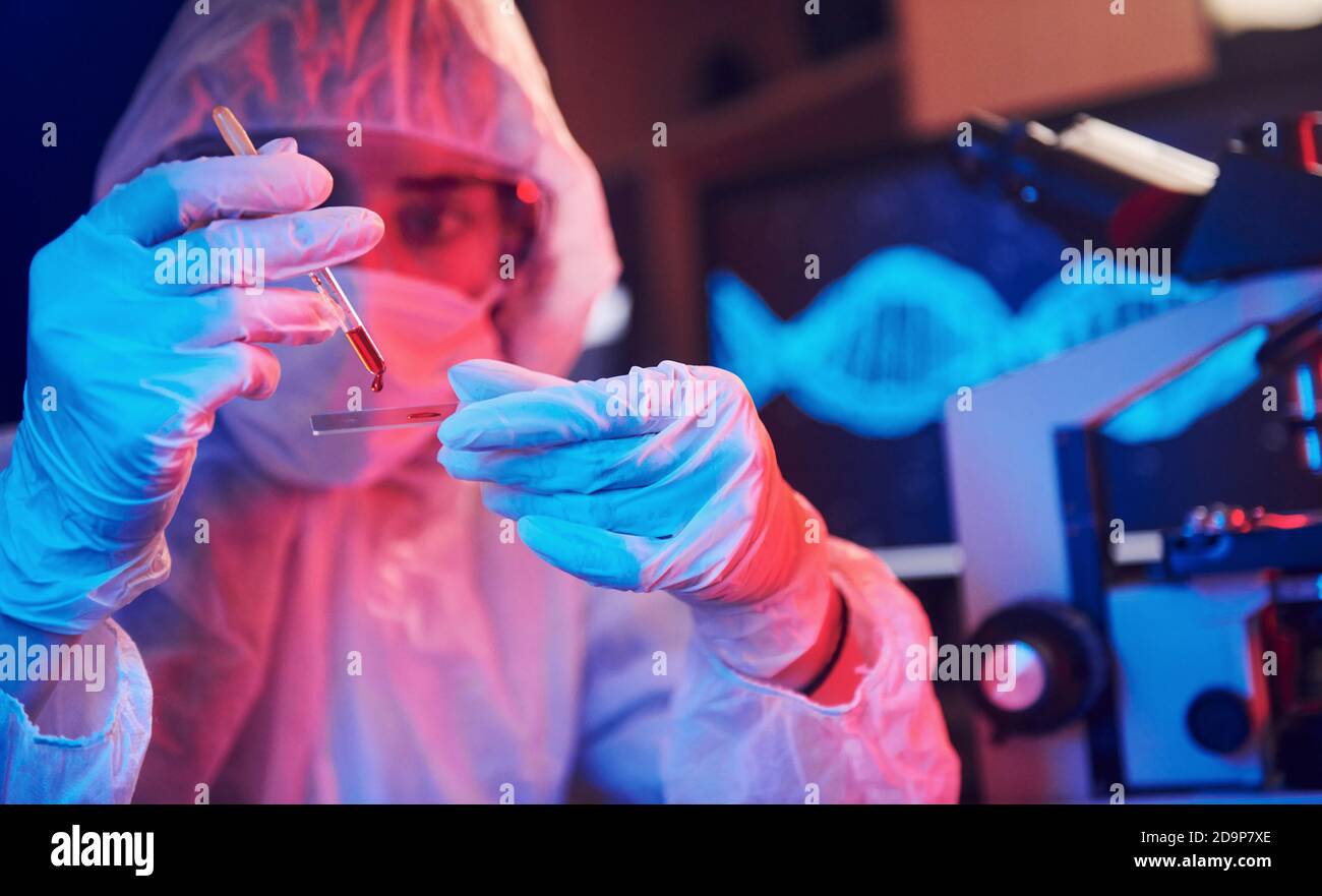 Nurse in mask and white uniform, holding tube with liquid and sitting ...