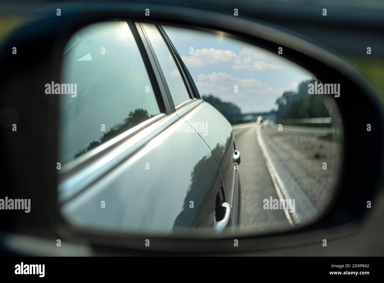 Reflection in the side mirror of a car driving on the highway, visible ...