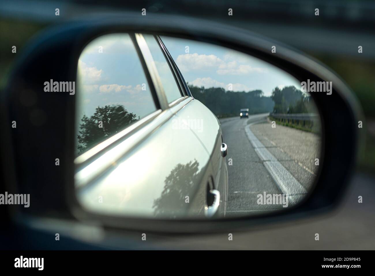 Reflection in the side mirror of a car driving on the highway, visible ...