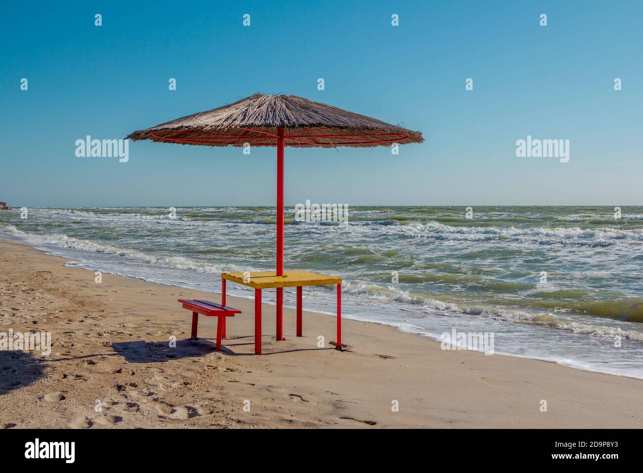 Summer landscape: table, benches and shade umbrella on the beach ...