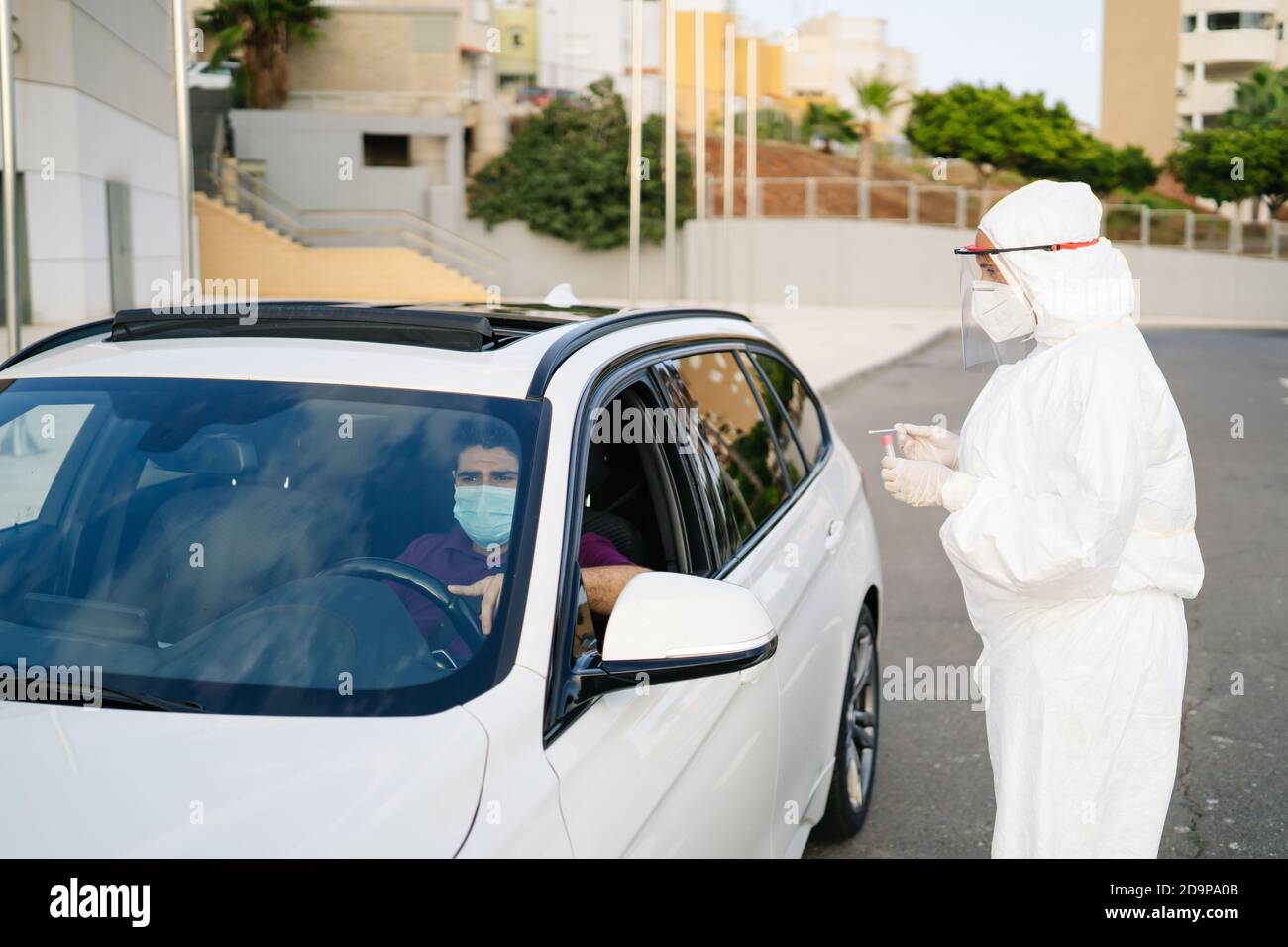 Doctor doing a PCR test COVID-19 on a patient through the car window ...