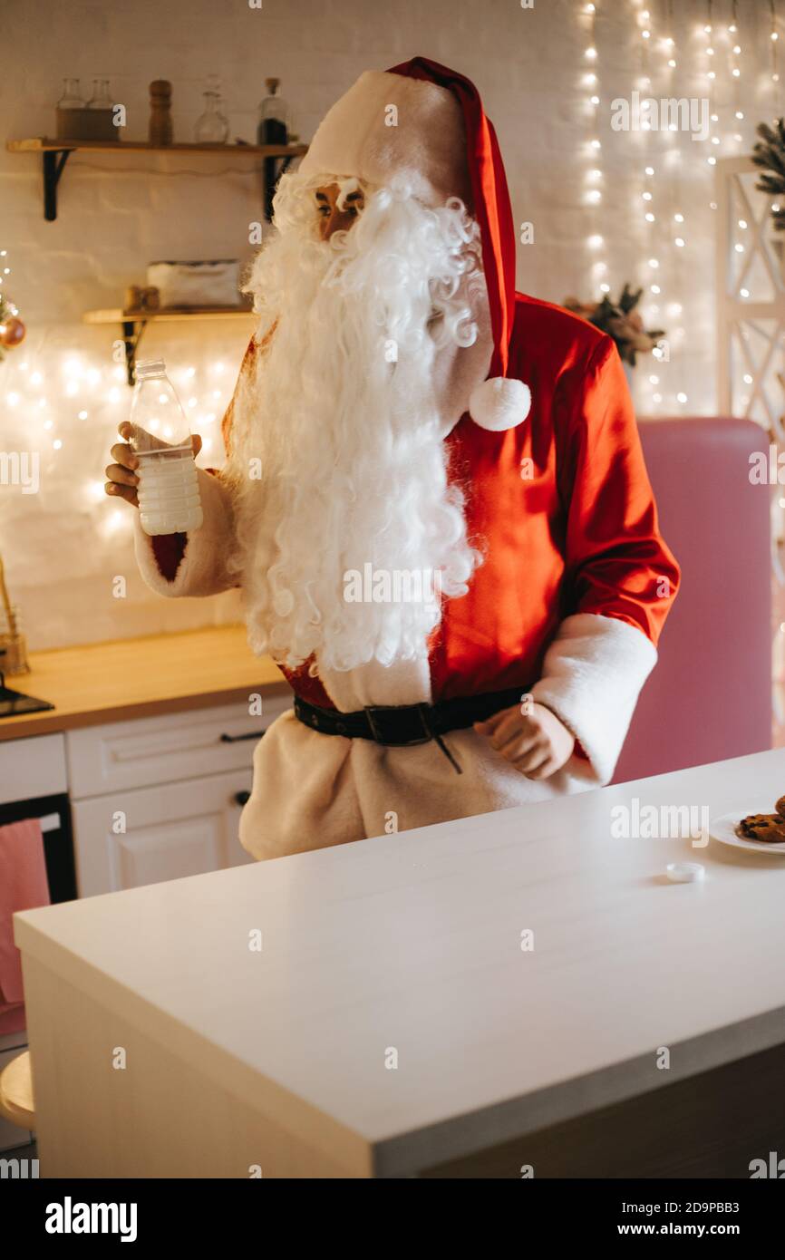 Santa Claus eating cookie and drinking milk at Christmas Stock Photo ...