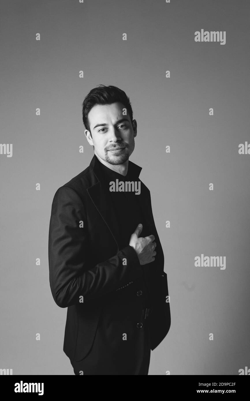 Studio portrait of a young caucasian man in a black blazer, looking at ...