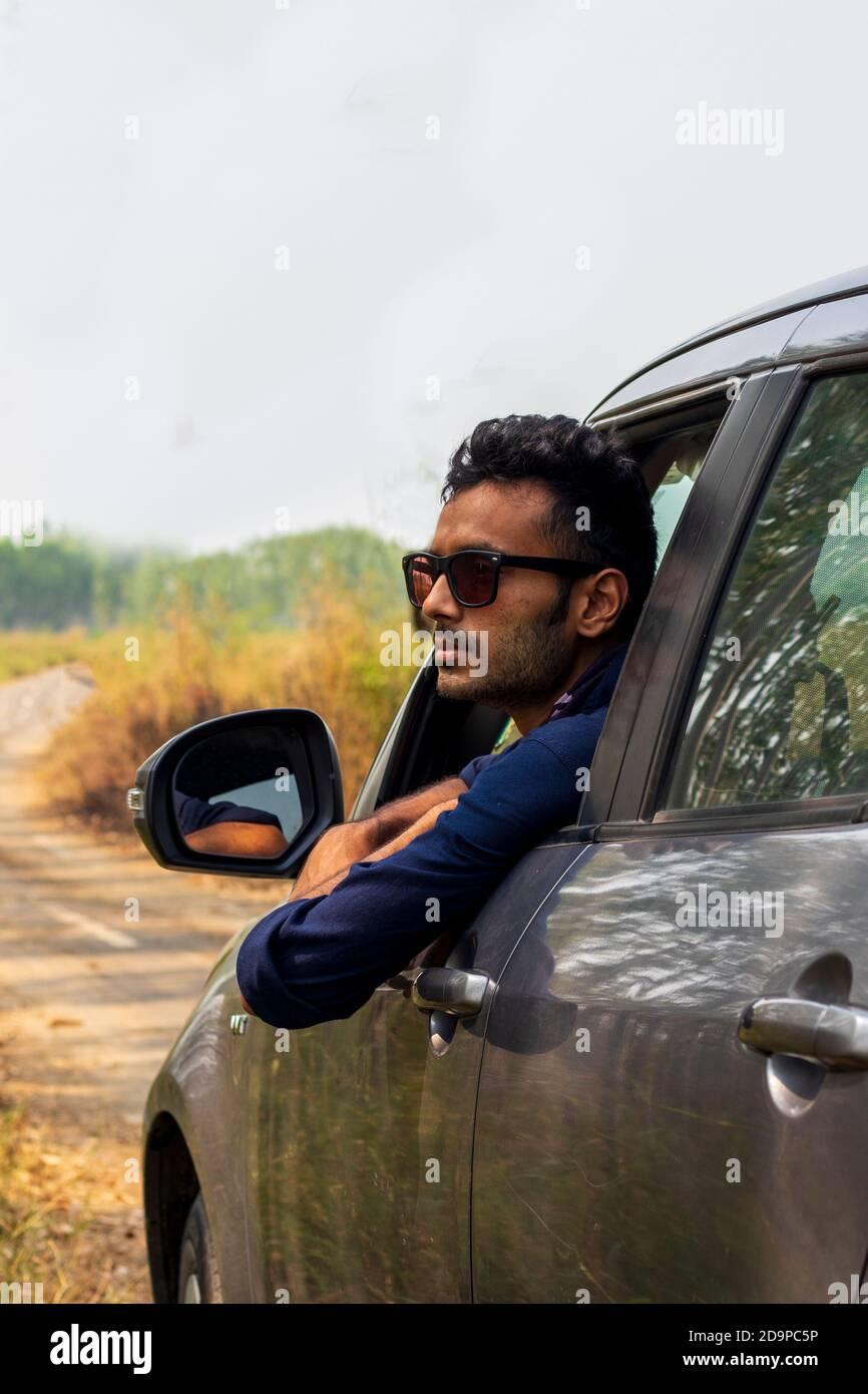Portrait of young indian man looking outside on car window Stock Photo ...