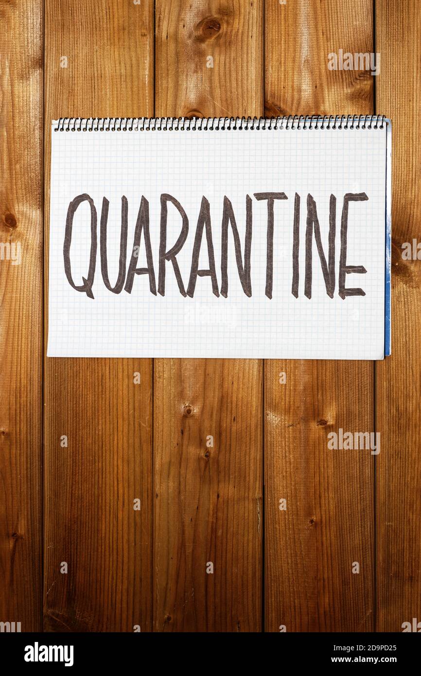 Closeup handwritten warning sign "Quarantine" on wooden wall or door ...
