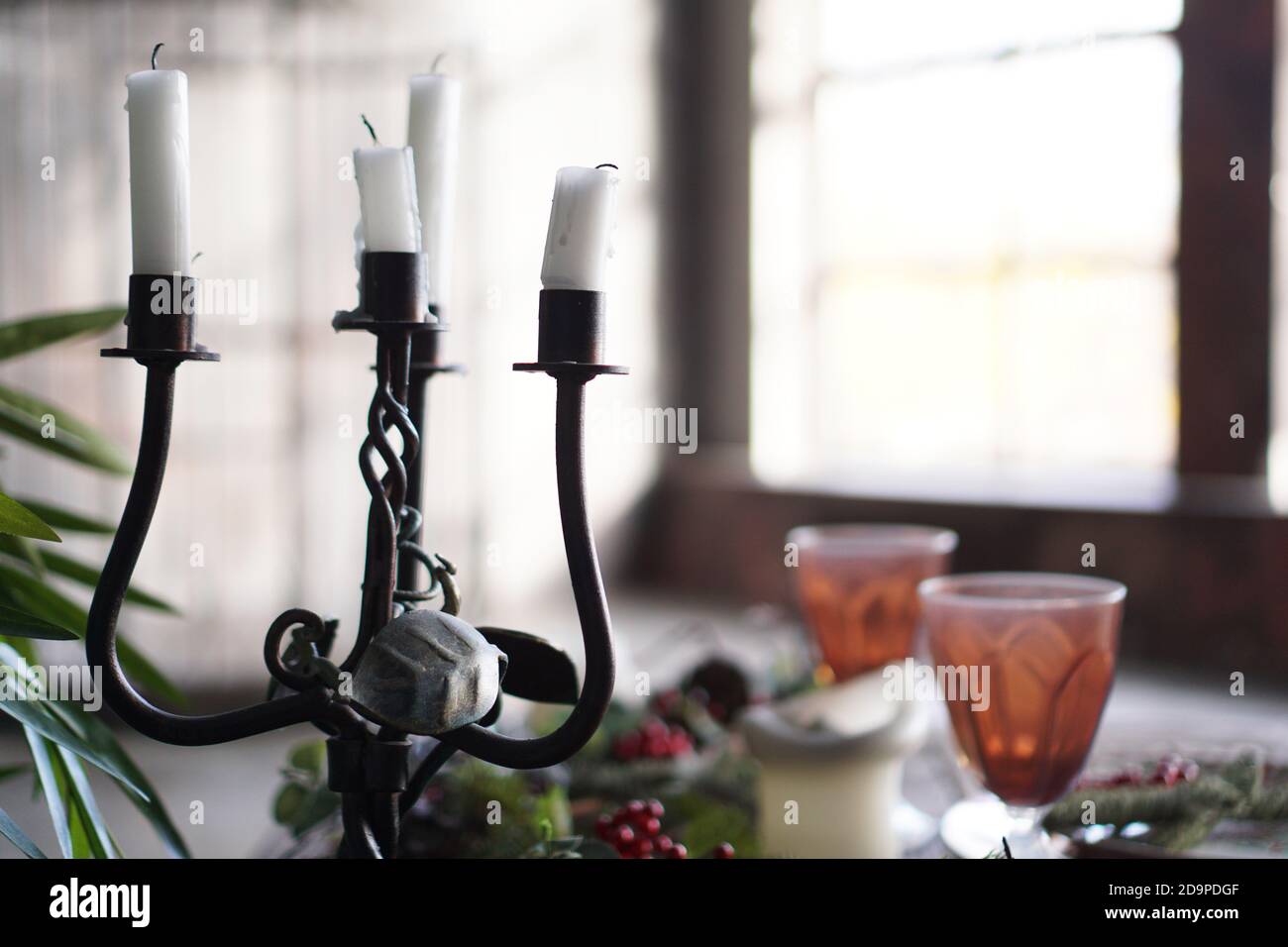 Forged metal candlestick with candles on blurred background with light ...