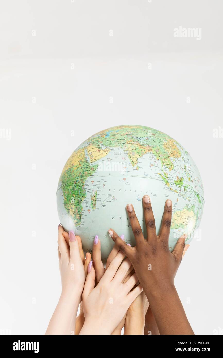 A large globe with all continents is supported by female hands of ...