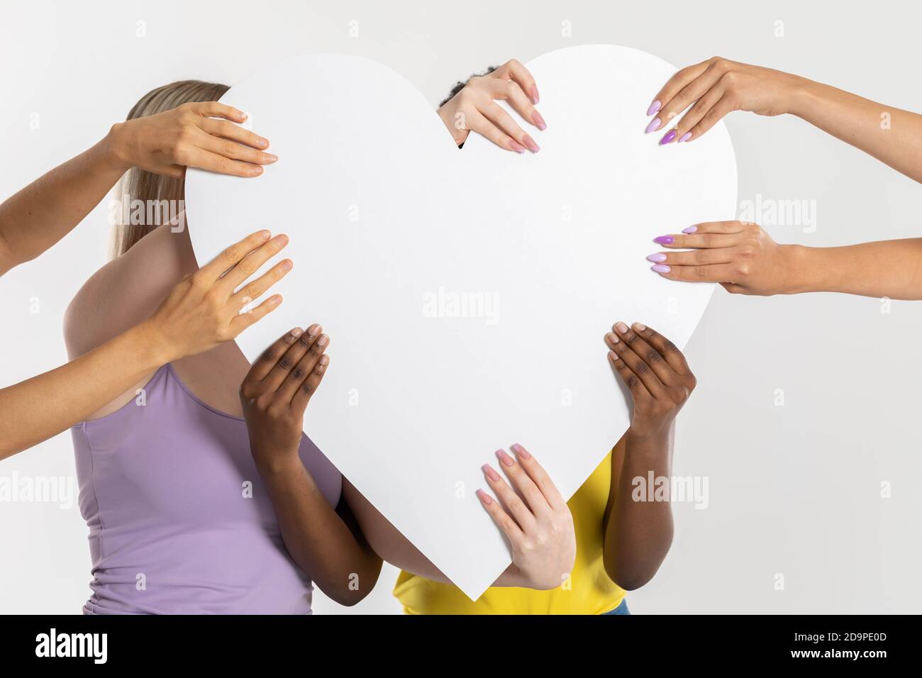 Heart shape held by female hands. Many women from different countries ...