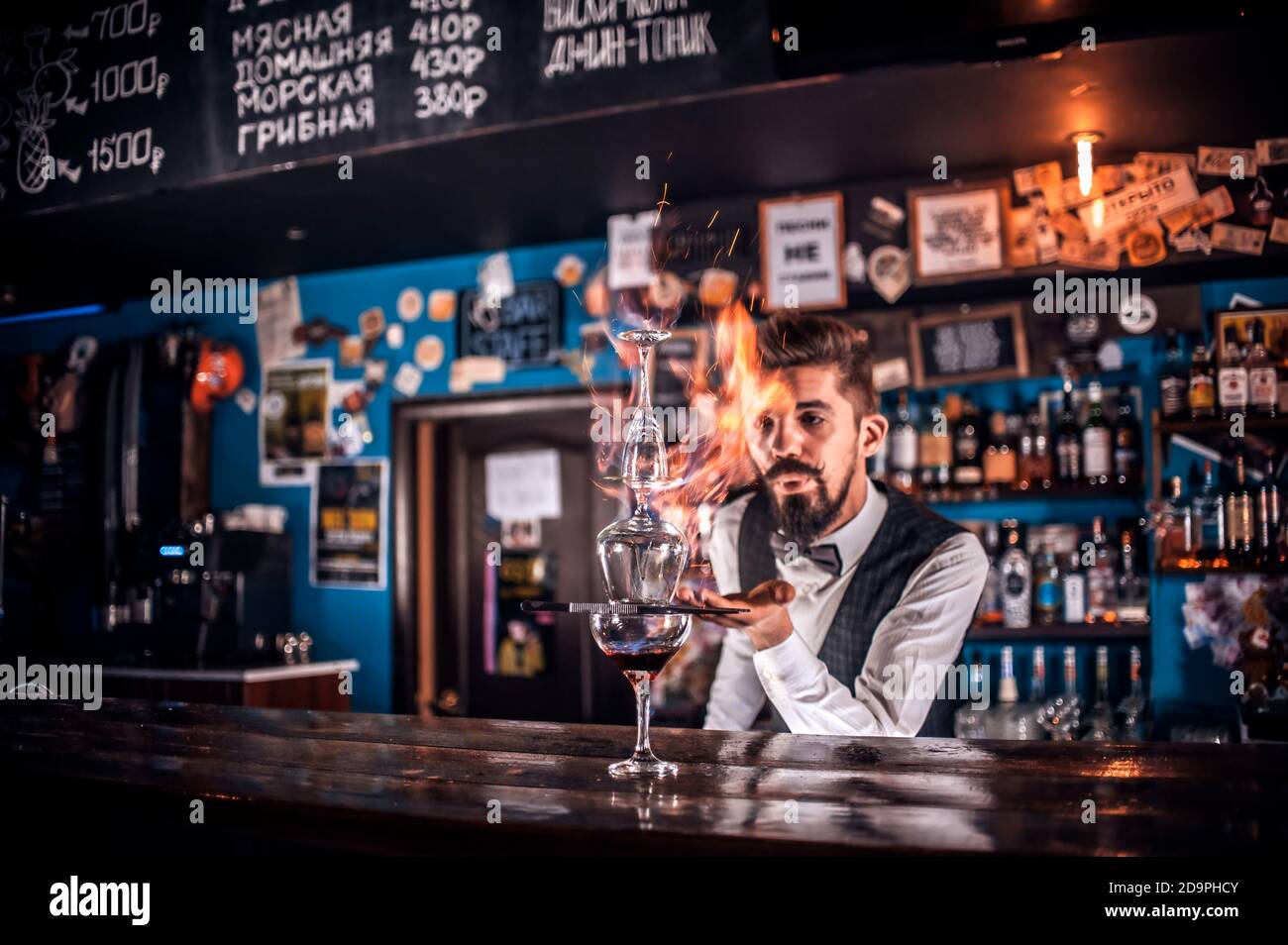 Bearded bartender demonstrates the process of making a cocktail in the ...