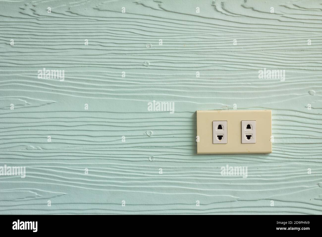 Wall outlets on the pale green wall with wood texture Stock Photo - Alamy