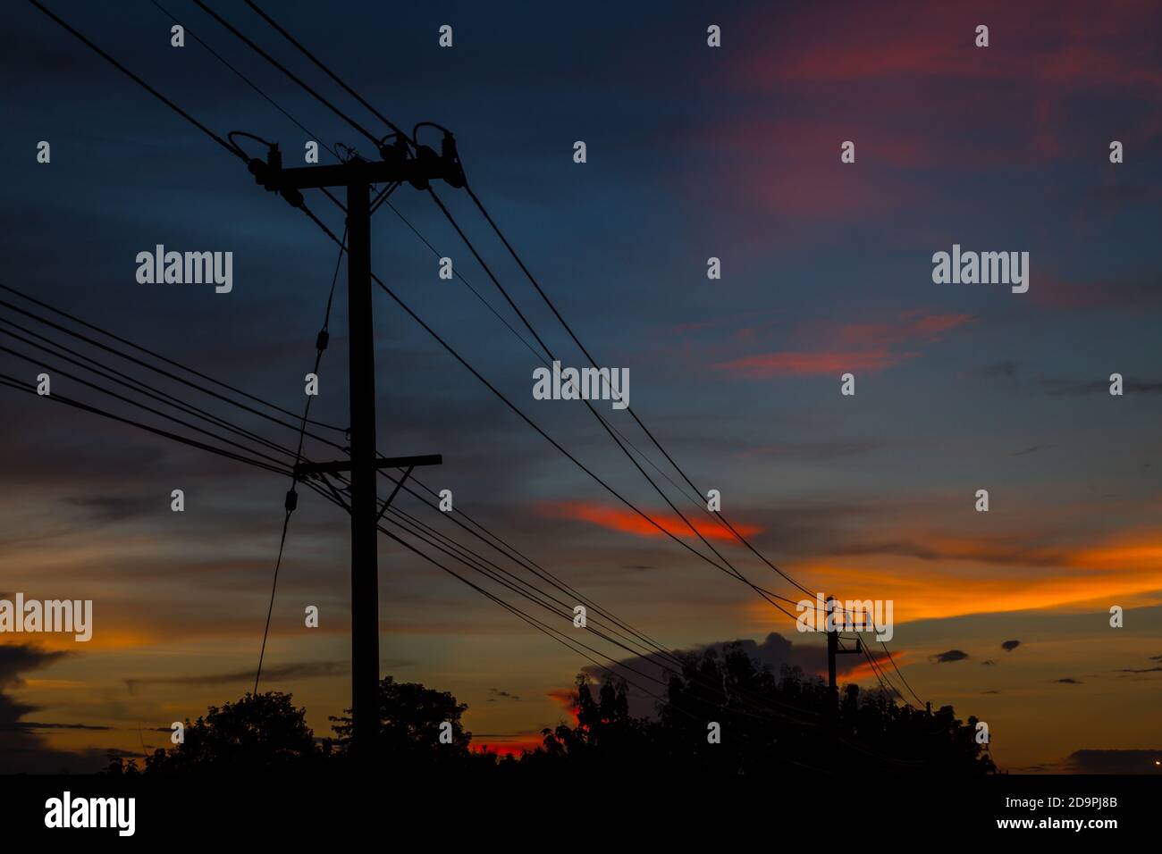 silhouette of electric post and wires in the background of twilight sky ...