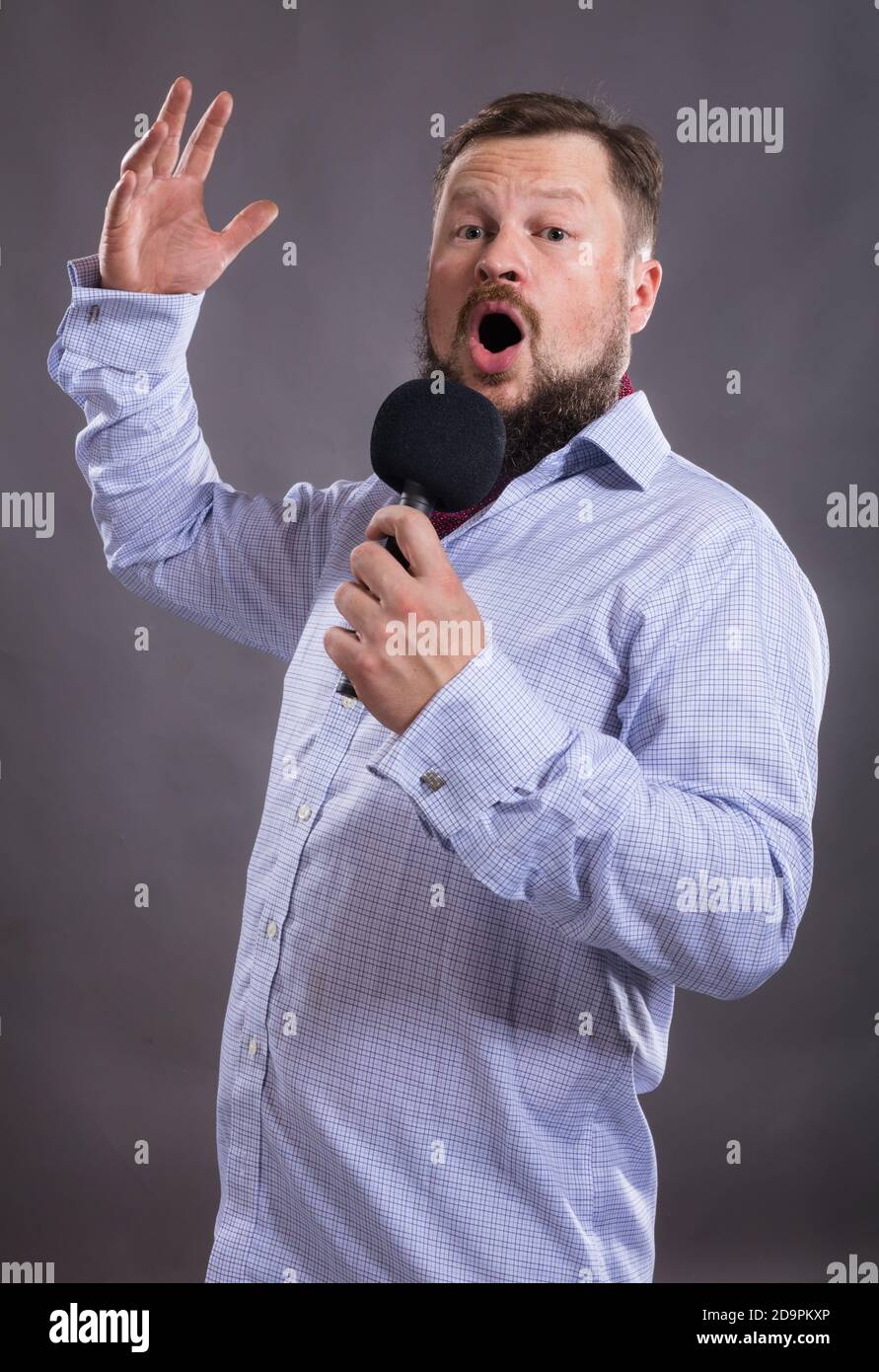 Bearded emotional singer with micriphone dressed in shirt studio ...