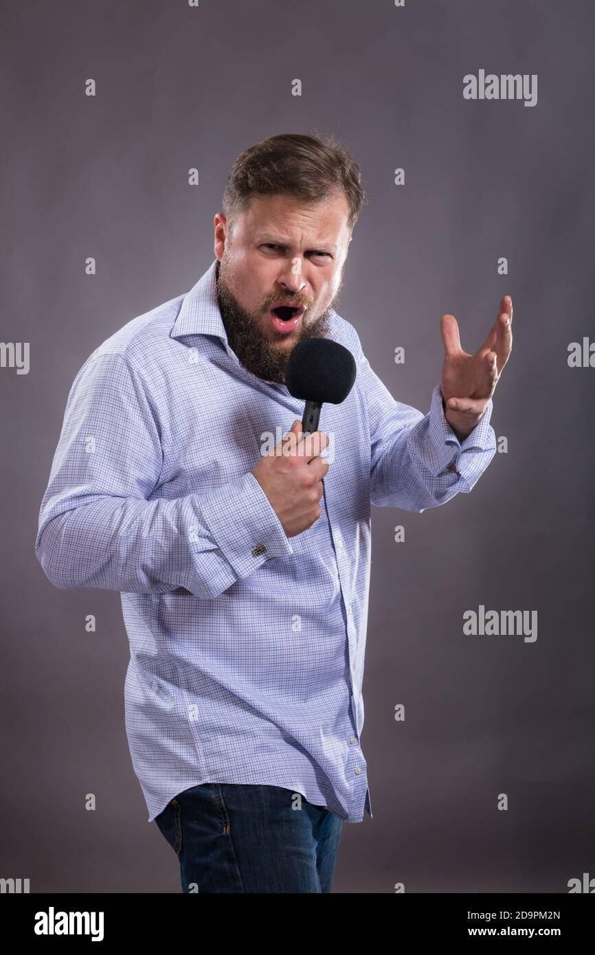 Bearded emotional singer with micriphone dressed in shirt studio ...