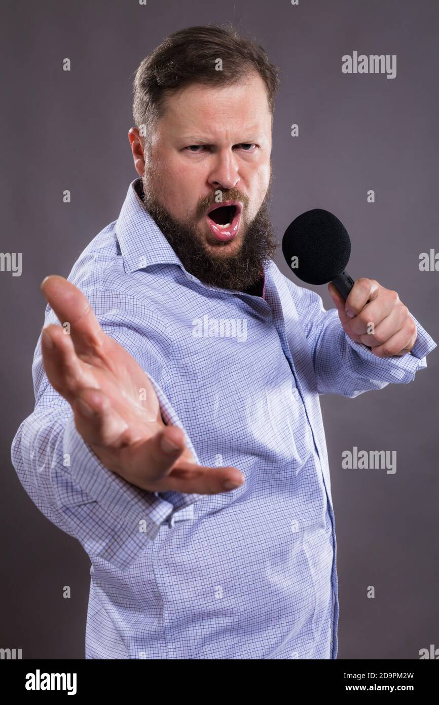 Bearded emotional singer with micriphone dressed in shirt studio ...