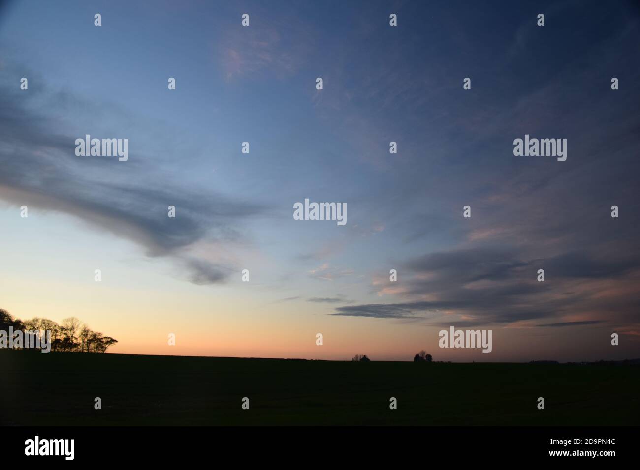 Cirrus type clouds tinged with colour from the setting sun highlighting ...