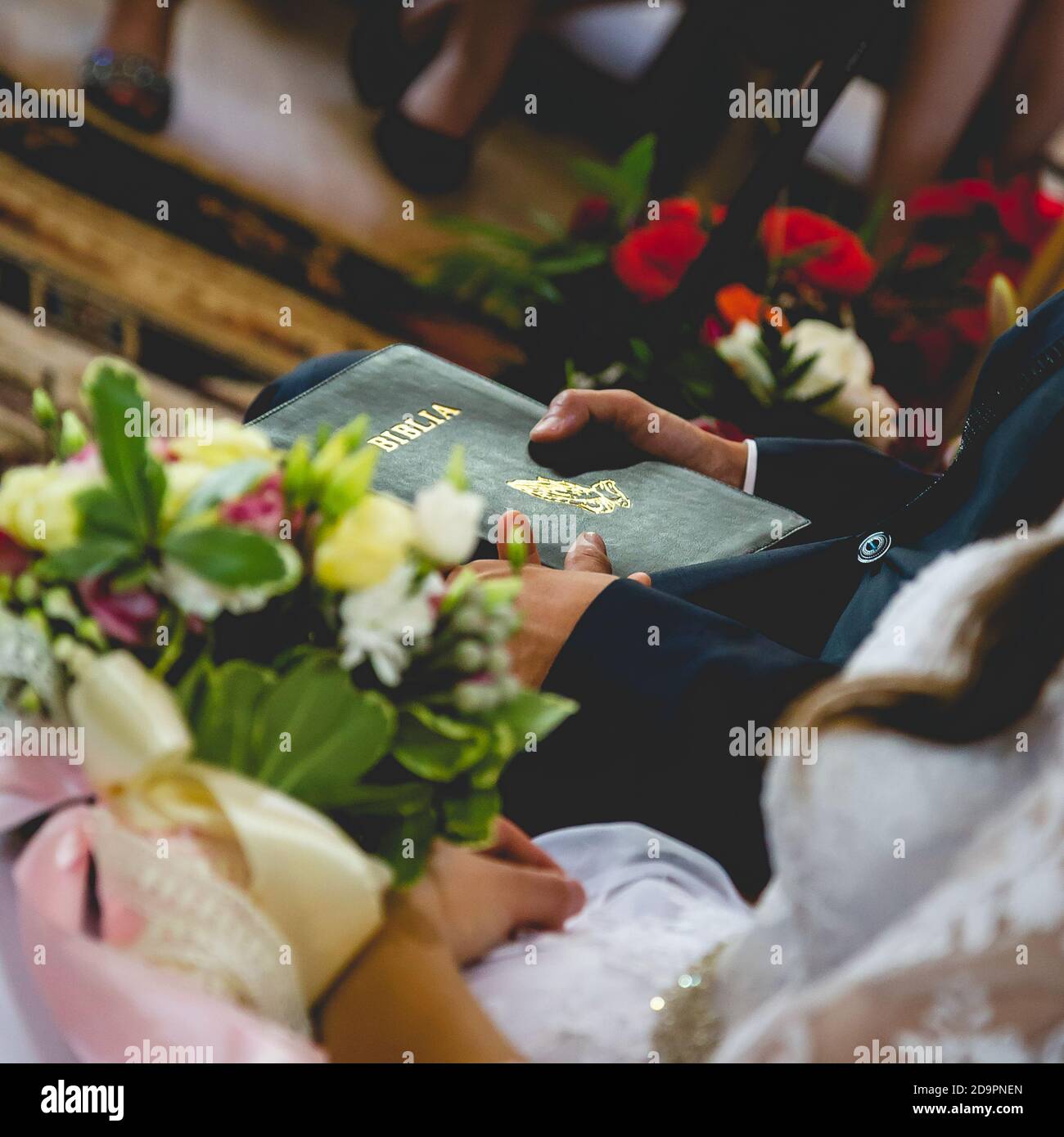 Vertical shot of the groom holding the bible while sitting by the bride ...
