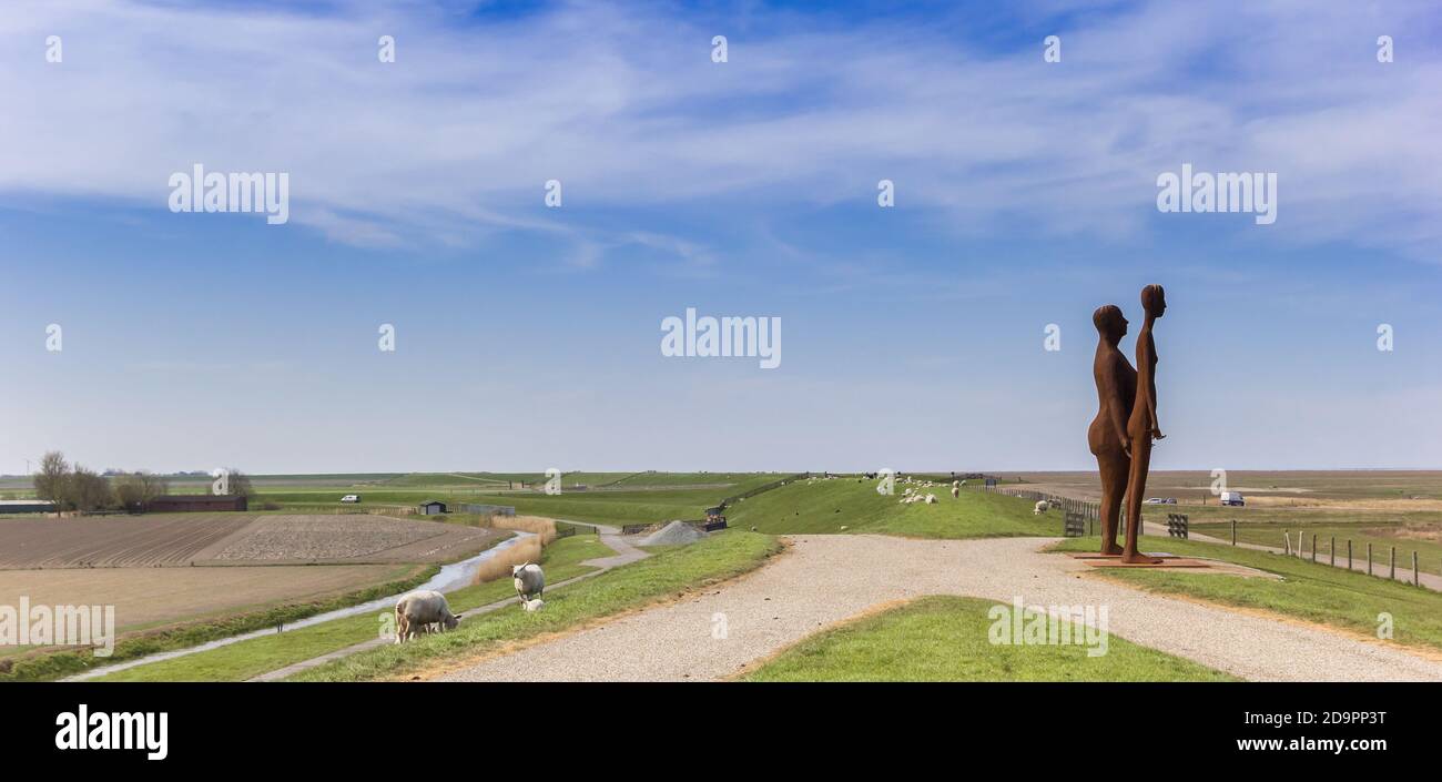 Panorama of a statue of a man and woman on a dike in Friesland ...