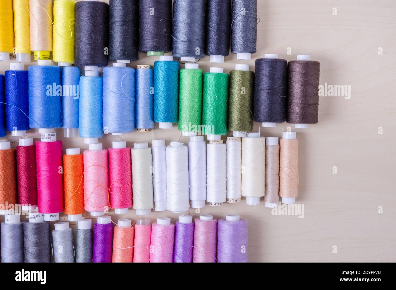 Flat lay of many spools with colorful threads on wooden desk or table ...