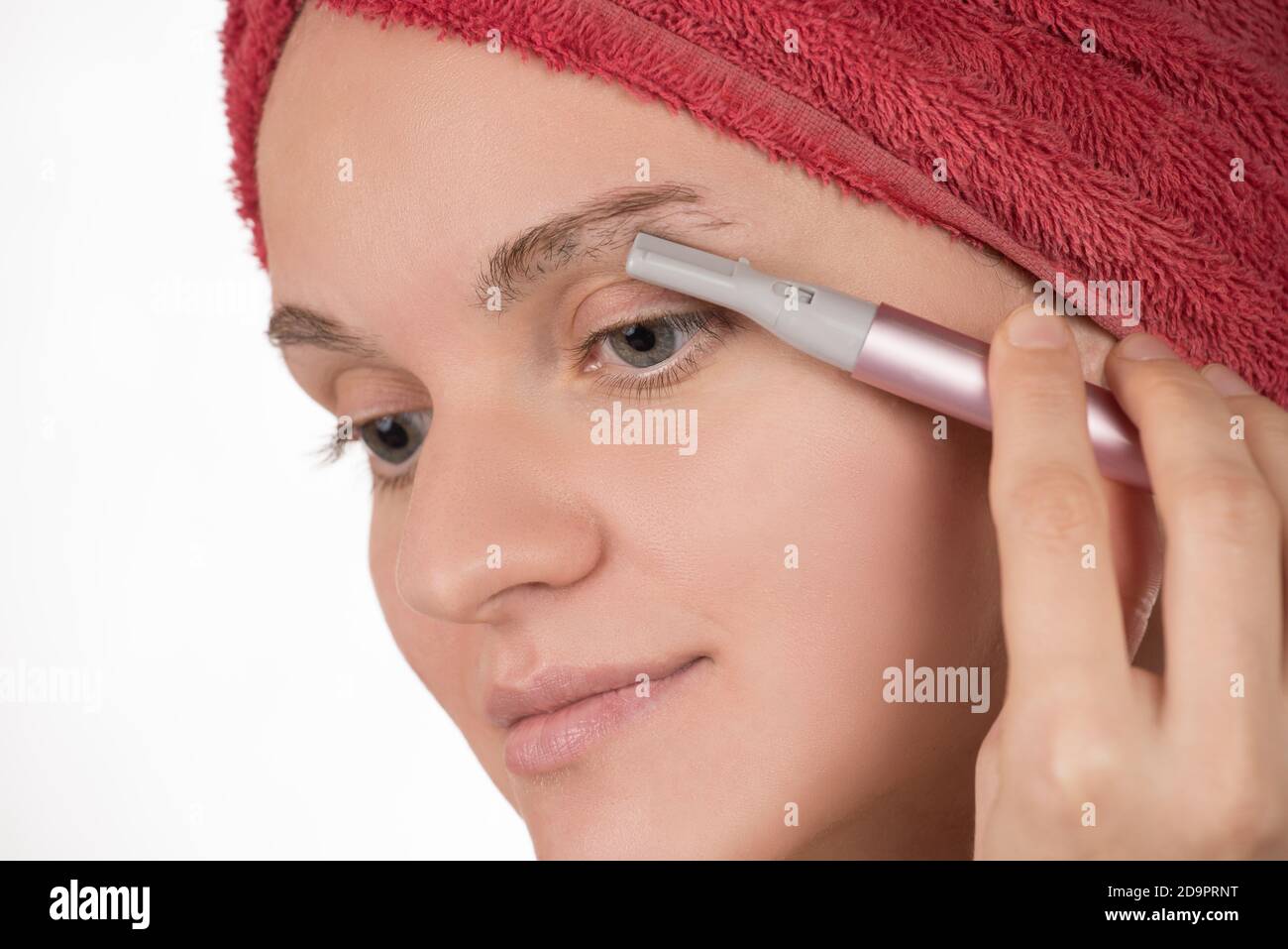 Young beautiful girl pulls out her eyebrows with tweezers metal on a ...