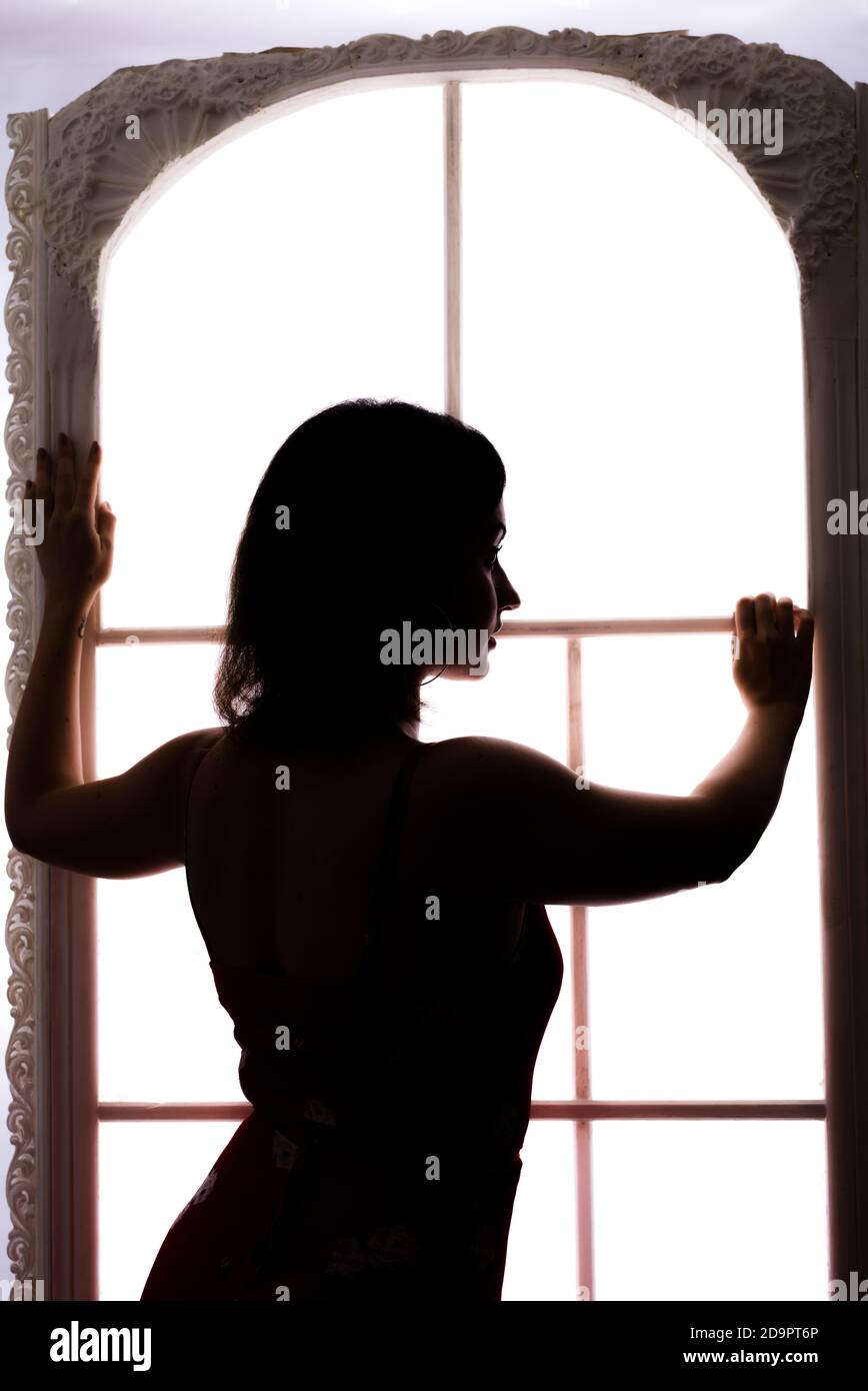 Woman's beautiful sihouette on white window background studio portrait ...