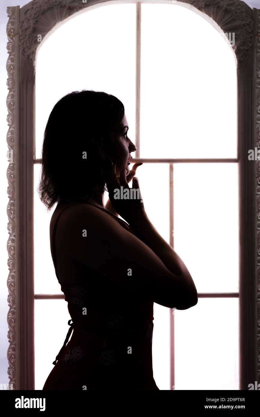 Woman's beautiful sihouette on white window background studio portrait ...