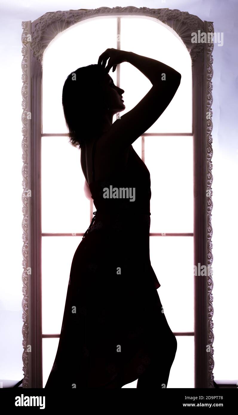 Woman's beautiful sihouette on white window background studio portrait ...