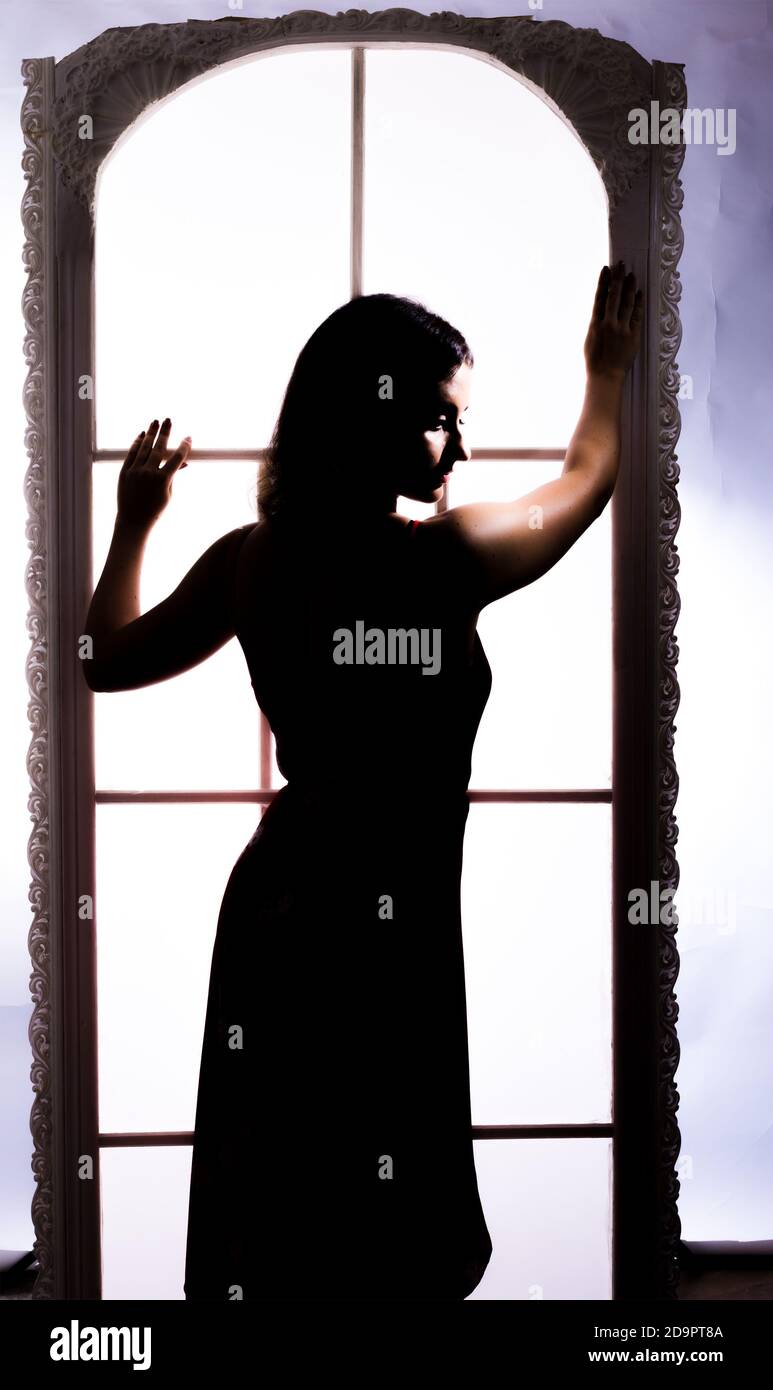 Woman's beautiful sihouette on white window background studio portrait ...