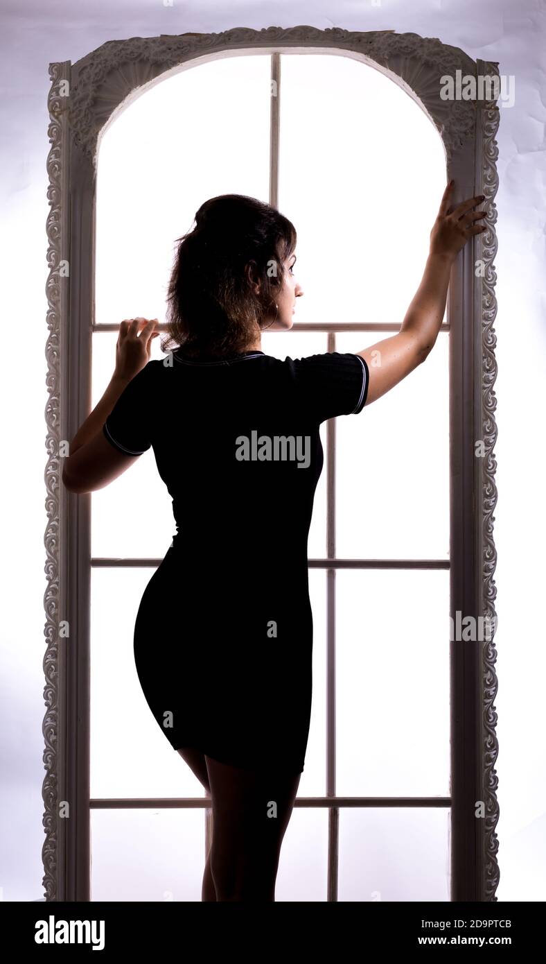 Woman's beautiful sihouette on white window background studio portrait ...